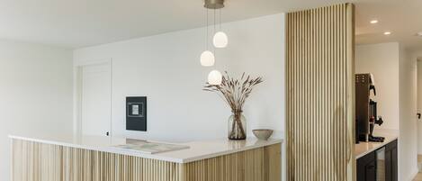 Uma área de recepção com um balcão de madeira, um vaso com galhos e uma máquina de café.