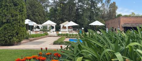 Um jardim com flores laranjas, um caminho e barracas brancas ao fundo.