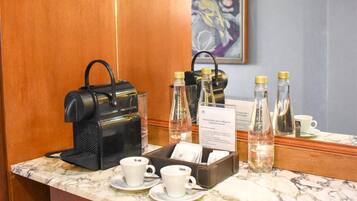 Minibar com máquina de café, duas chávenas e uma garrafa de água.