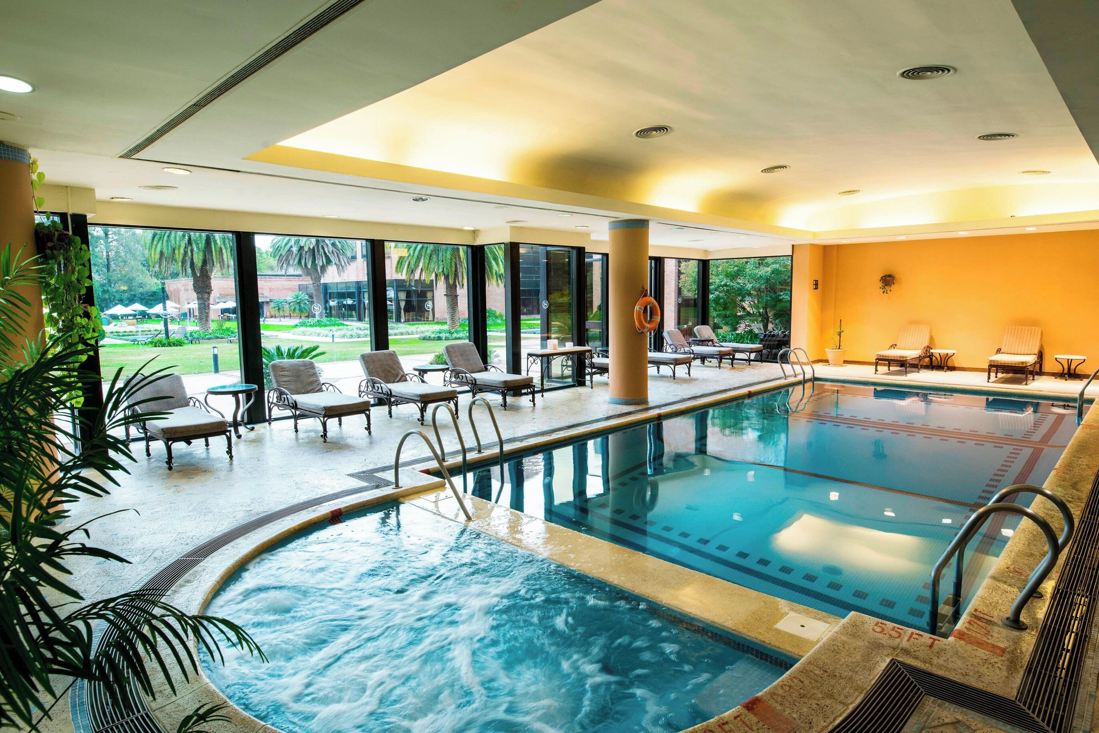 Piscina com espreguiçadeiras e vista para o jardim.
