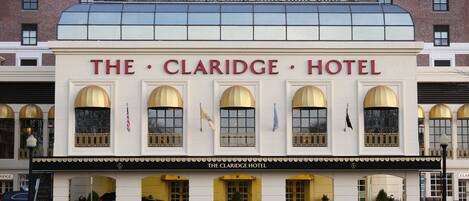 Fachada do Hotel Claridge com janelas em arco, toldo amarelo e bandeiras.