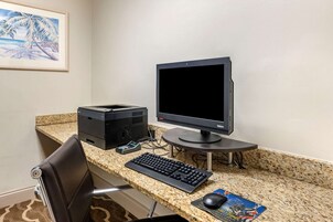 Um espaço de escritório em casa com um computador desktop, teclado, rato e monitor sobre uma bancada de granito.