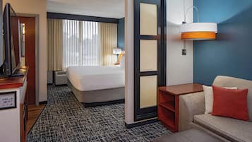 Quarto de hotel com cama, sofá, escrivaninha e banheiro.