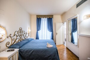 Quarto com cama, mesa de cabeceira, espelho e janela com cortinas.