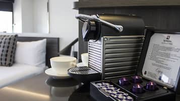 Máquina de café Nespresso com manual, duas chávenas e um tabuleiro com cápsulas de café sobre uma mesa.