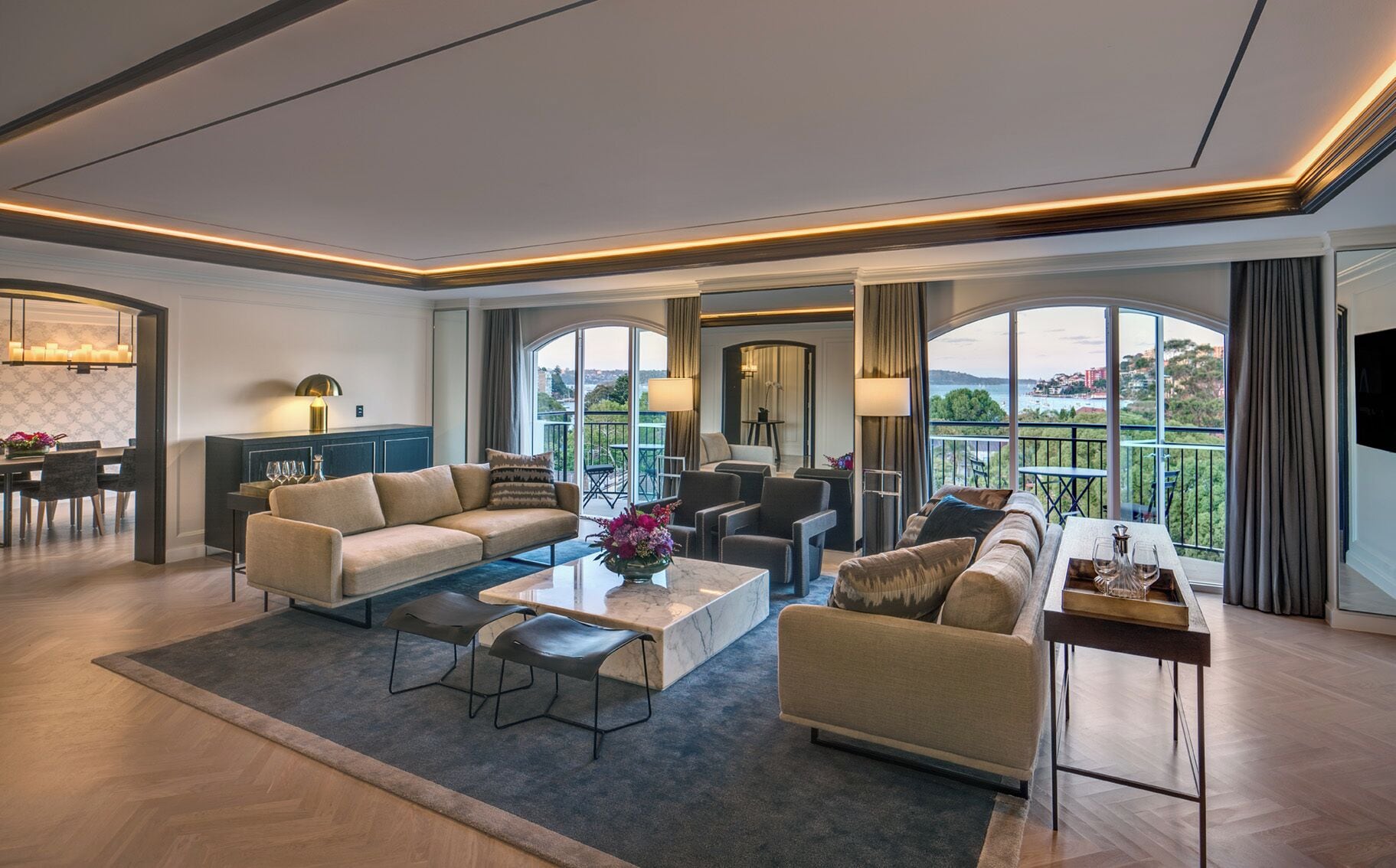 Quarto de hotel moderno com área de estar, espaço para refeições e varanda com vista para a cidade.