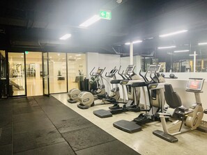 Uma academia com esteiras, elípticos e plataformas de step.