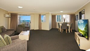 Quarto de hotel com sala de estar, mesa de jantar e televisão.
