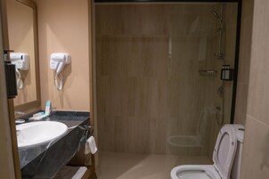 Casa de banho com lavatório, espelho, secador de cabelo e chuveiro.