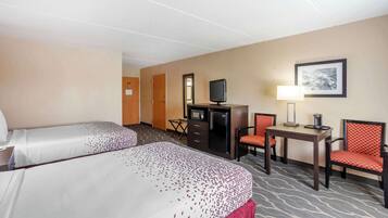 Quarto de hotel com duas camas, uma escrivaninha, uma televisão e uma cadeira.