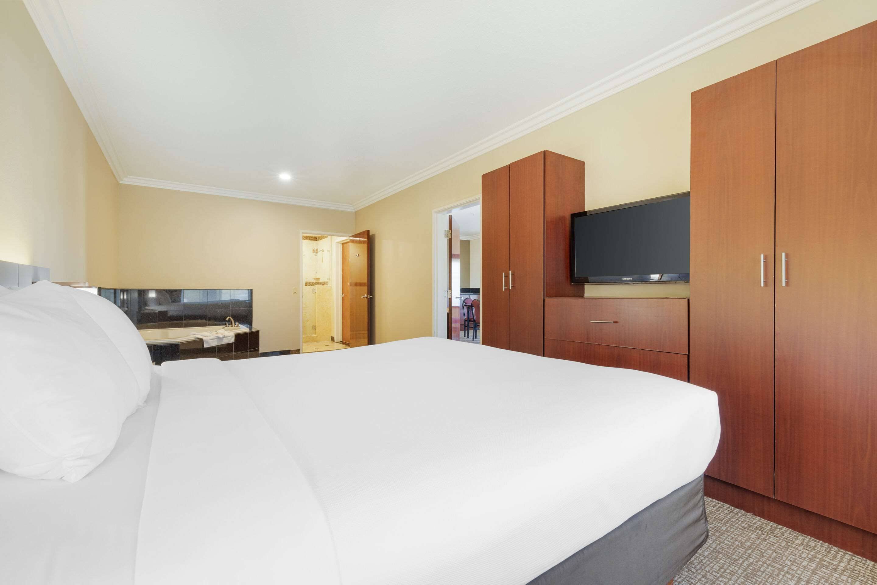 Quarto de hotel com uma cama grande, guarda-roupa de madeira e televisão de tela plana.