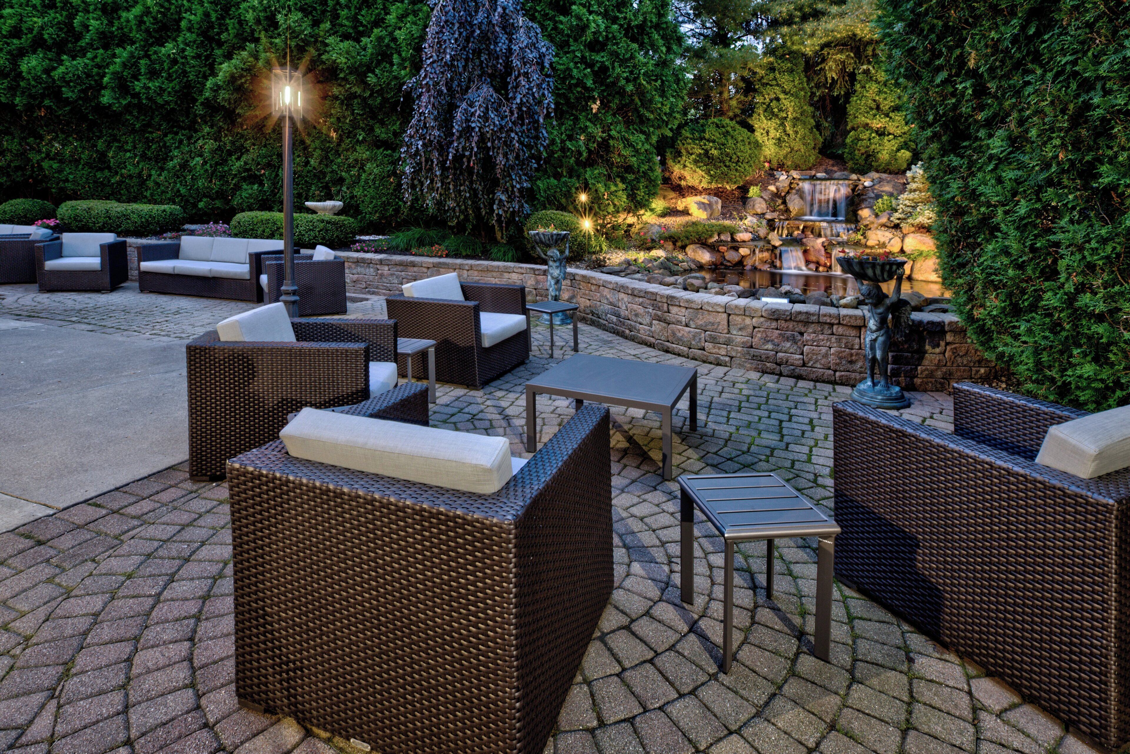 An outdoor patio area with wicker furniture and a stone wall.