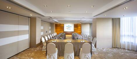 Uma sala de conferências com uma mesa comprida, cadeiras e uma tela exibindo 'The Harbourview'.