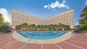 Um hotel grande com piscina, vários andares e fachada curva.