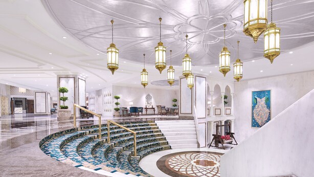 Um hall imponente com uma escadaria de mármore, lustres elaborados e uma obra de arte central.