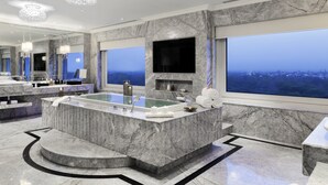 Um banheiro luxuoso com uma ampla banheira de mármore, uma pia dupla e uma grande janela com vista para a cidade.