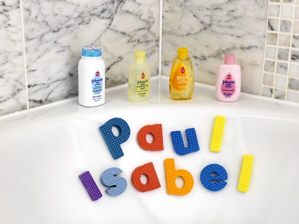 Casa de banho com lavatório de mármore e artigos de higiene pessoal, incluindo produtos para bebé.