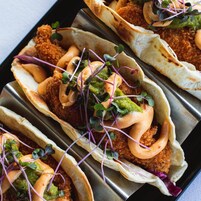 Uma bandeja com pratos de comida, provavelmente tacos, com diversos acompanhamentos e guarnições.