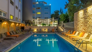 Piscina com espreguiçadeiras e um muro de pedra.
