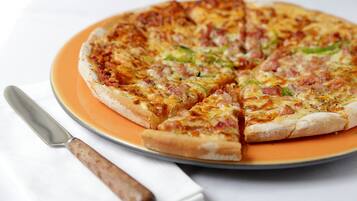 Pizza em um prato com uma faca e guardanapo ao lado.