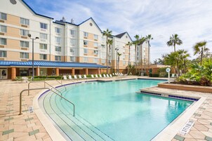 Um hotel com piscina, espreguiçadeiras e palmeiras.