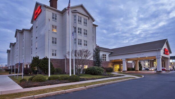 Um hotel com uma bandeira americana em destaque, entrada visível e gramado bem cuidado.