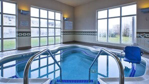 Piscina com água azul cristalina, rodeada por janelas e um chão revestido com azulejos.