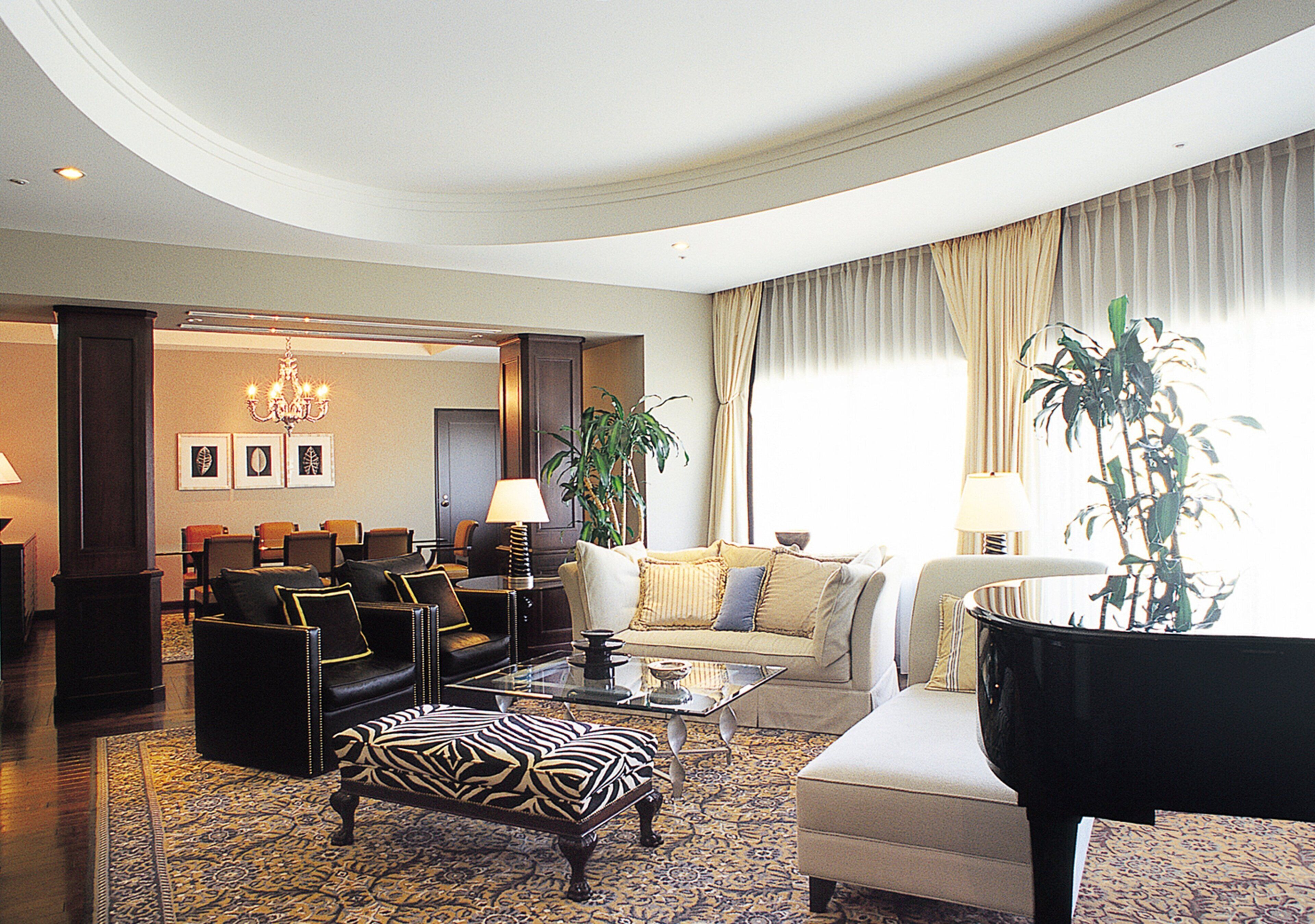 Um hall de hotel espaçoso com área de estar, um candelabro e uma grande janela com cortinas.