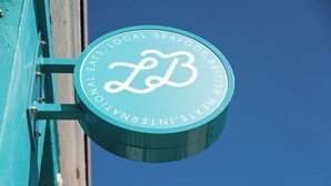 Sinal redondo com o texto 'PEIXE LOCAL, BRITÂNICO' e um logotipo estilizado de 'B'.