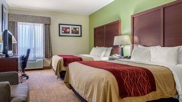 Quarto de hotel com duas camas, uma escrivaninha com cadeira, televisão e janela com cortinas.