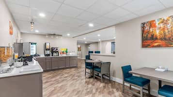 Cozinha moderna com ilha central, espaço para café e área de refeições com cadeiras azuis e uma mesa.