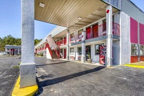 Um motel com estrutura de dois andares, área de estacionamento coberta e uma escadaria visível que leva à entrada.