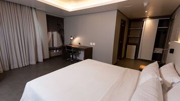 Quarto de hotel moderno com uma cama grande, uma escrivaninha com cadeira, um guarda-roupa e uma casa de banho.
