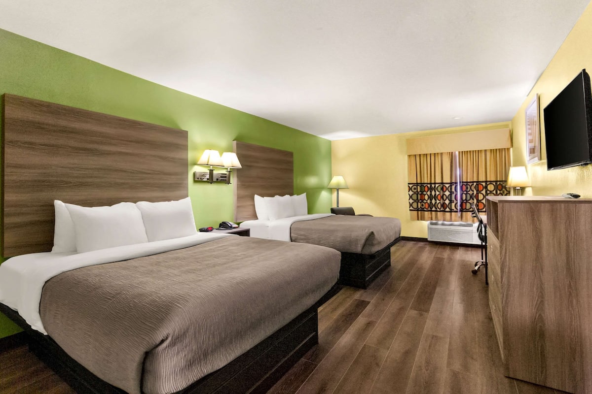 Quarto de hotel com duas camas, uma escrivaninha, televisão e minibar.