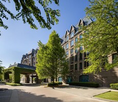 Um hotel de vários andares com entrada coberta, grandes janelas e um gramado bem cuidado.