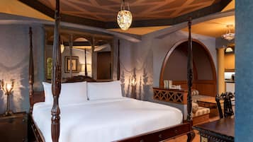 Uma cama de dossel com cortina, um criado-mudo de madeira, um espelho e um lustre.