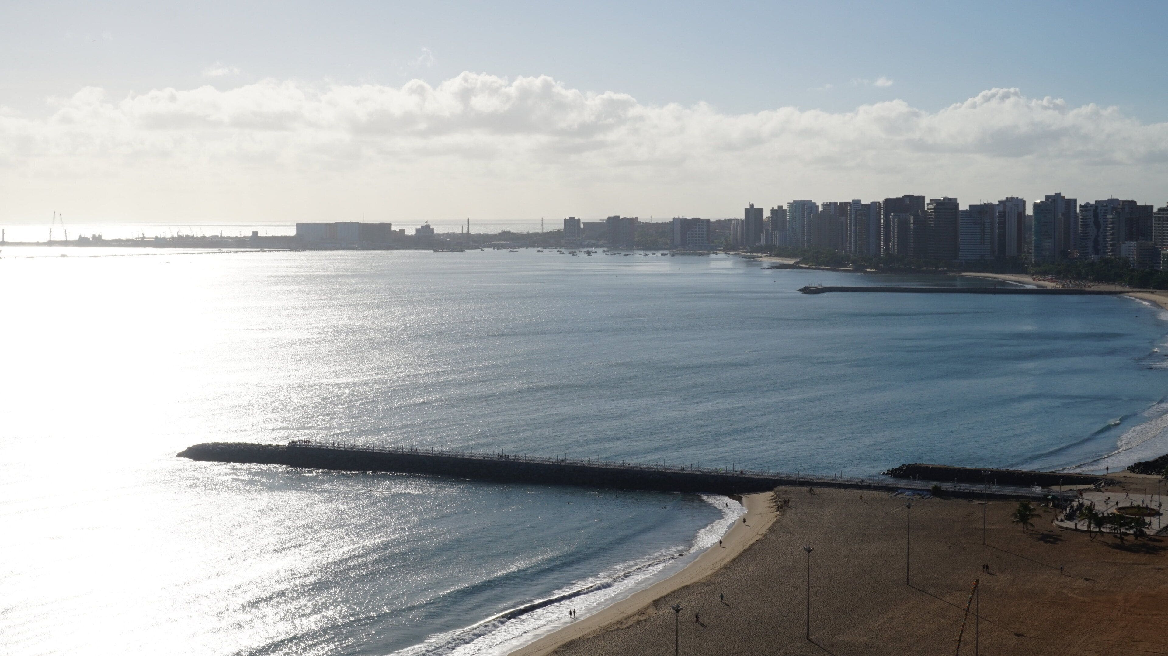 Paisagem costeira urbana com praia, calçadão e edifícios altos.