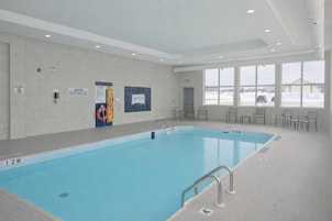 Piscina com profundidade de 1,2m, área de estar interna e grandes janelas.