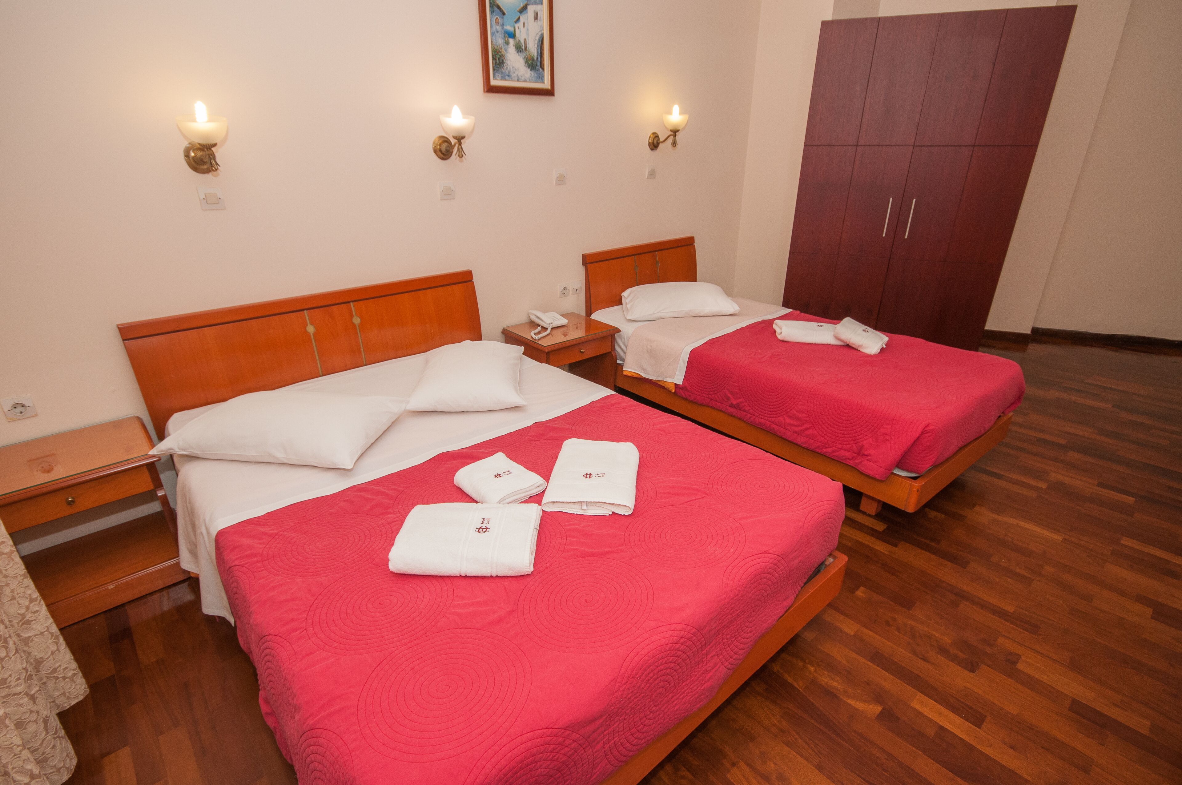 Quarto de hotel com duas camas, cabeceiras de madeira e um guarda-roupa.