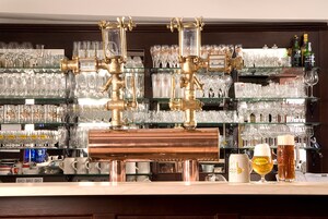 Uma área de bar com torneiras de cobre, copos e garrafas.