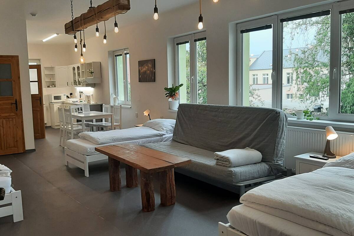 Um quarto acolhedor e bem iluminado, com sofá, mesa de madeira e cozinha.