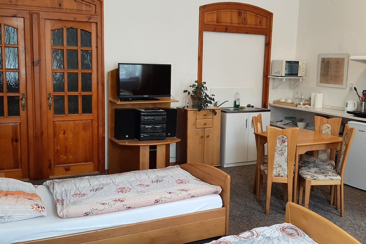 Quarto compacto com cama, escrivaninha, cadeira, televisão, micro-ondas e frigorífico.