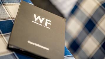 Um livreto preto com a inscrição 'WF WATERFOOT HOTEL' e 'Informações para hóspedes'.