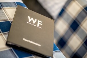 Um livreto preto com a inscrição 'WF WATERFOOT HOTEL' e 'Informações para hóspedes'.