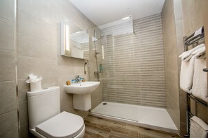 Uma casa de banho moderna com sanita, lavatório e cabine de duche em vidro.