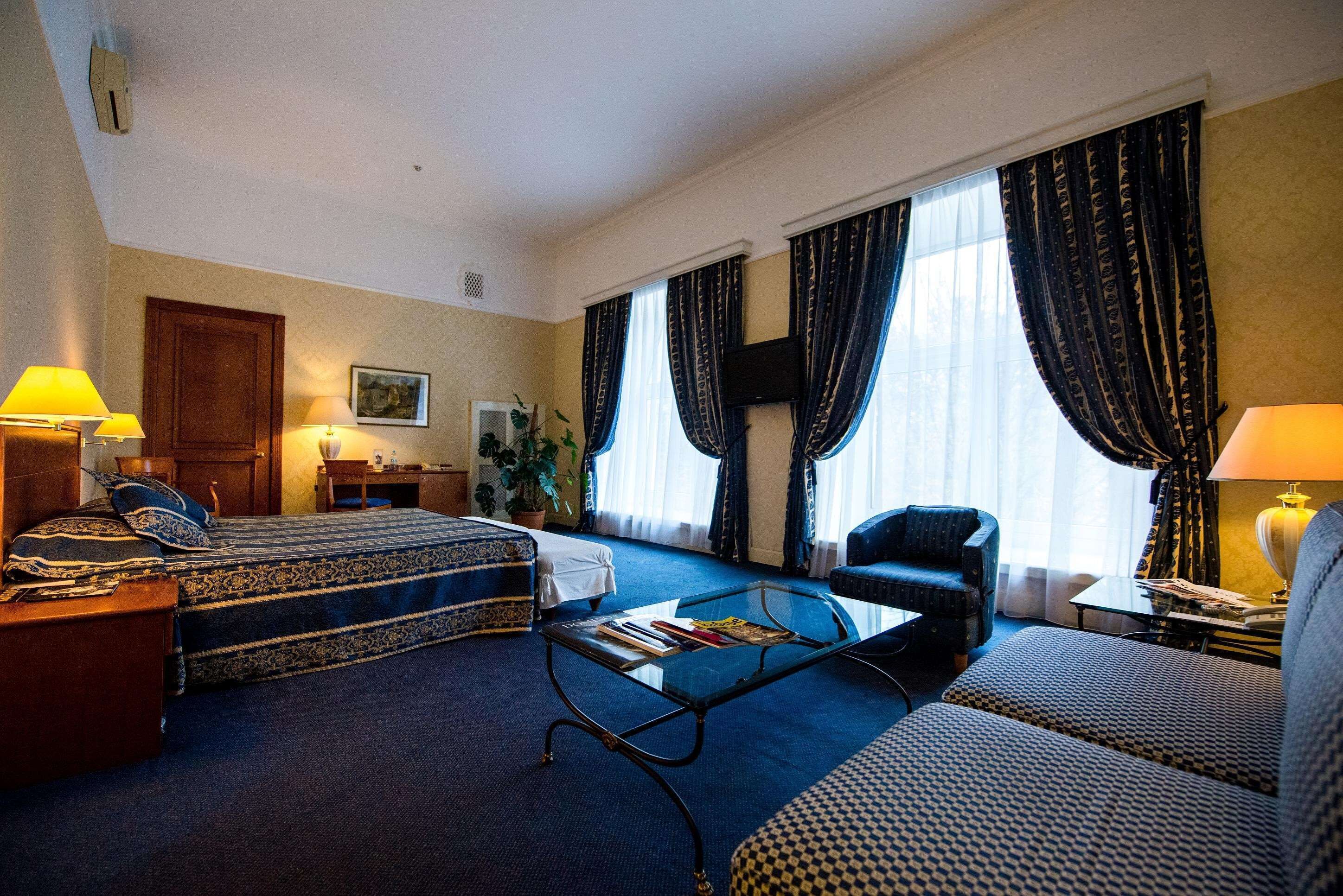 Quarto de hotel com duas camas, um sofá, uma mesa de centro, uma escrivaninha e uma televisão.