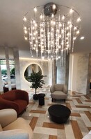 Um interior moderno com um lustre central, um espelho redondo e uma planta em vaso.
