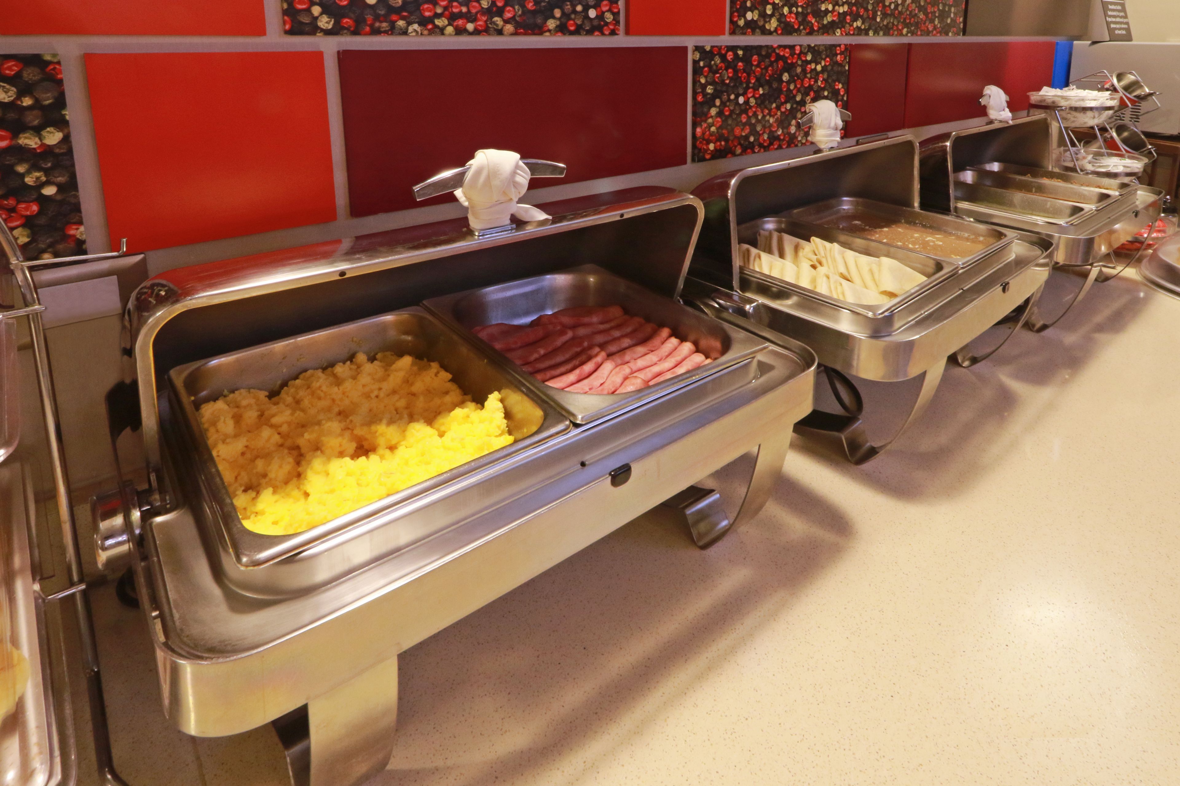 Buffet com diversas opções de comida, incluindo arroz, cachorros-quentes e outros pratos.