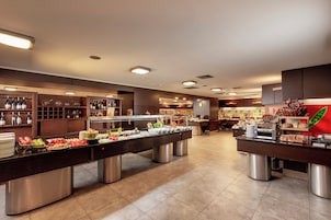 Uma área de buffet com diversas estações de comida, seleção de vinhos e um bar de café.