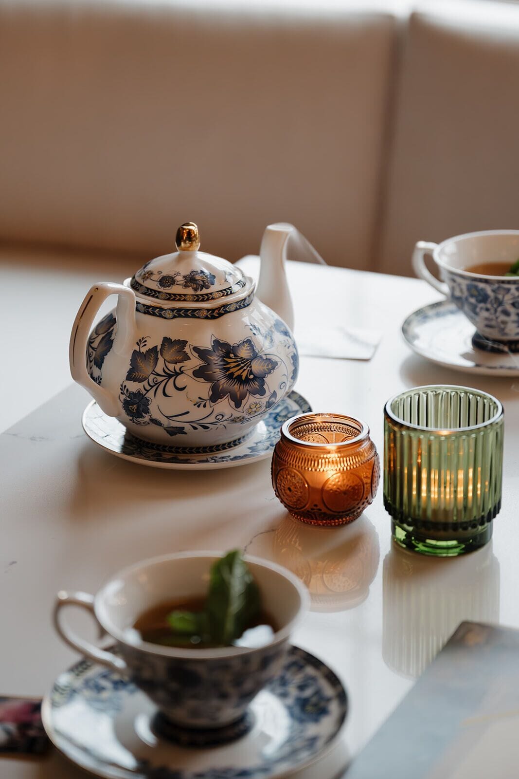 Uma mesa com um bule, xícaras e uma vela.